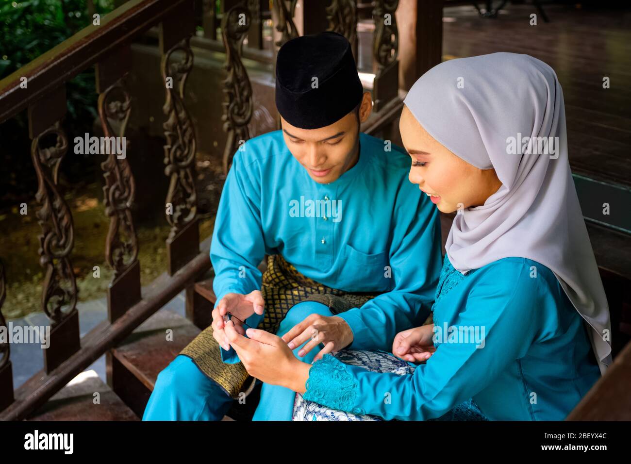 Young couple of malay muslim in traditional costume watching online ...