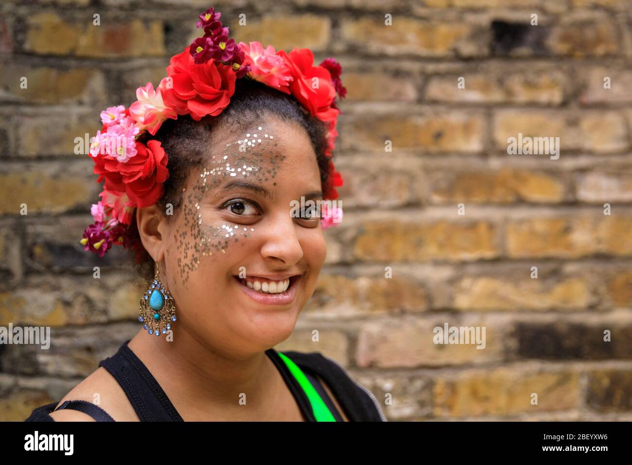 Participant with decorated face and flower head piece and revellers at ...