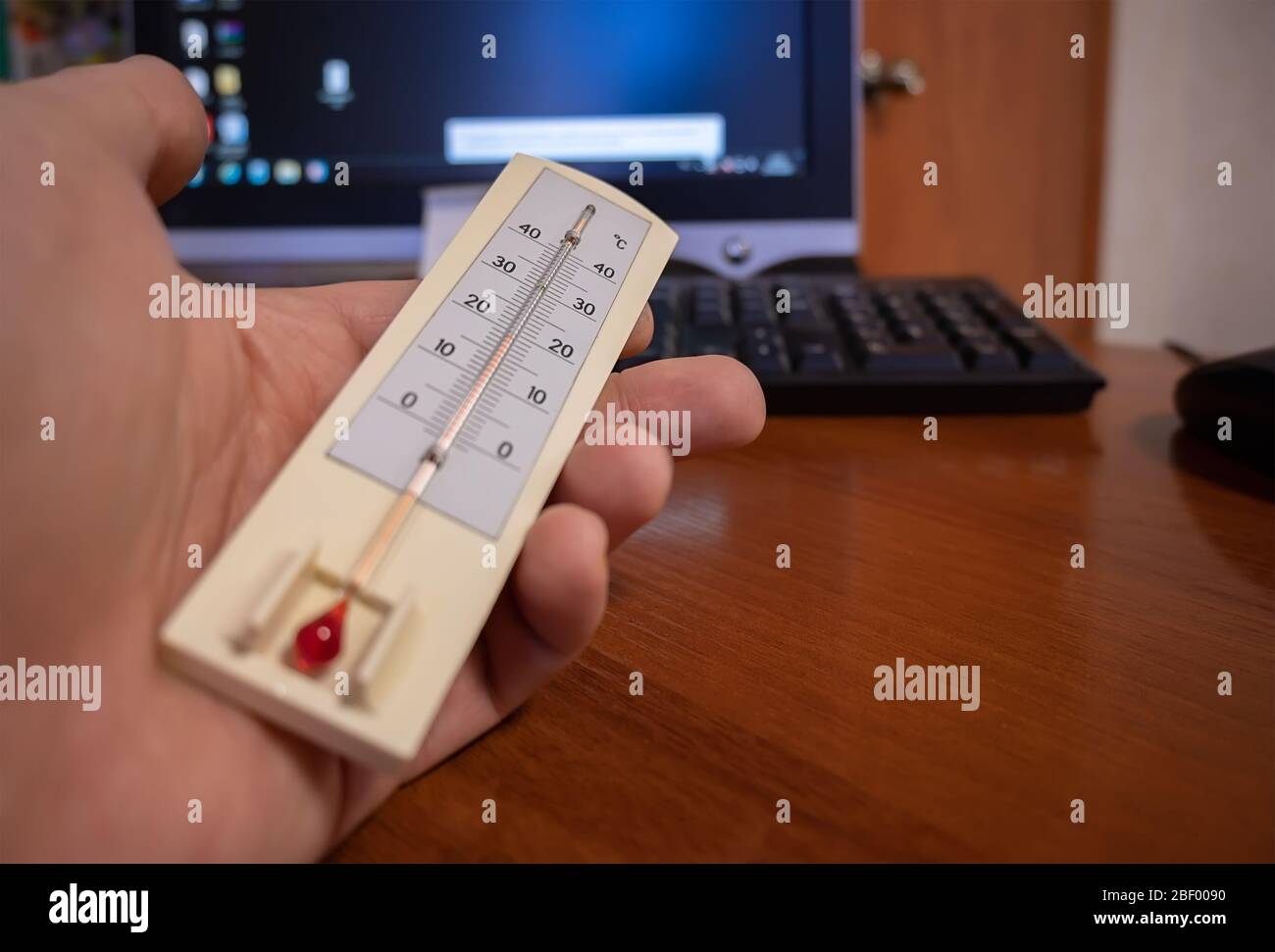 thermometer in the hand of an office worker, showing the low ...