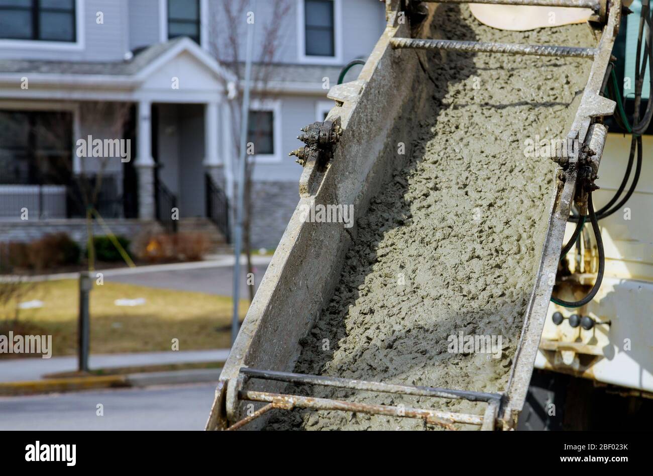 Pouring cement in process of pouring concrete into newly paved sidewalk ...