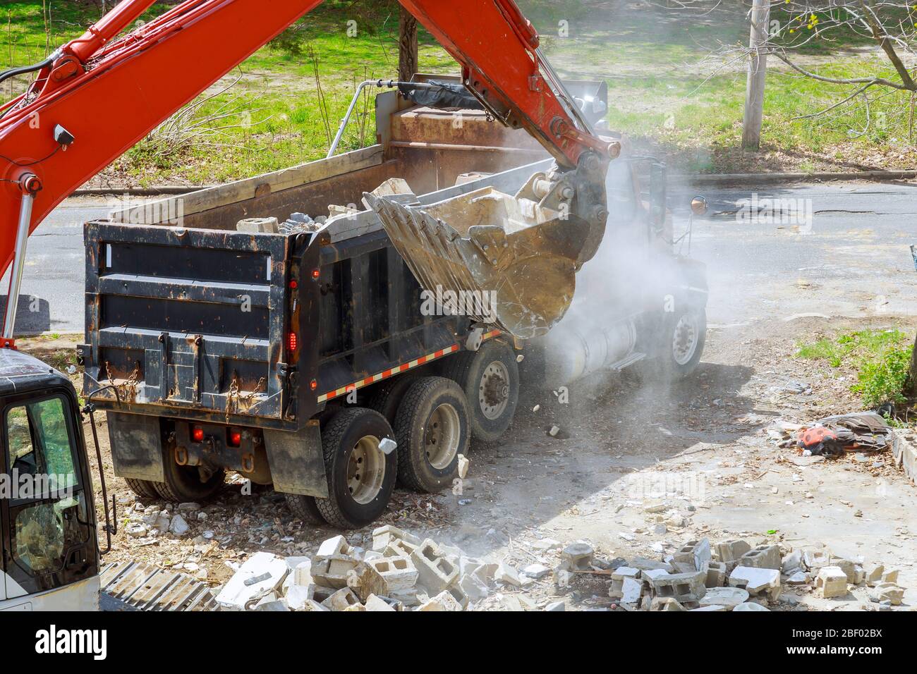 Excavator scoop truck loading a construction waste into reinforced ...