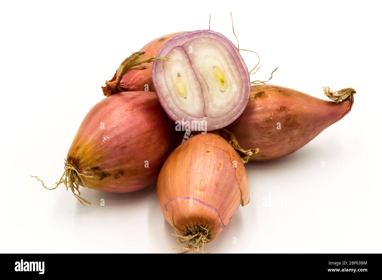 Vegetables: several isolated shallots, one cut in half on a white ...
