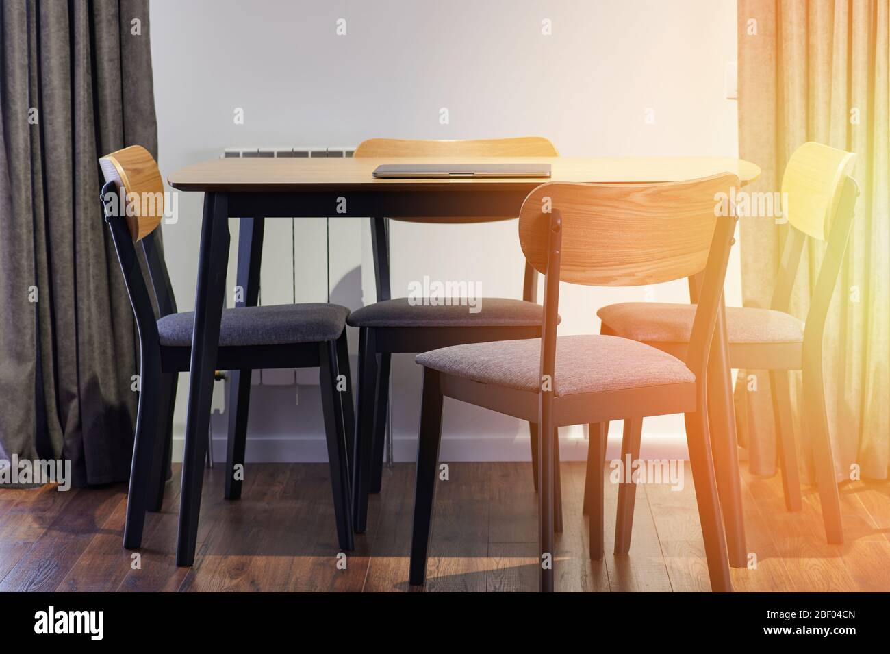 Modern wooden table with laptop and chairs around inside of apartment ...