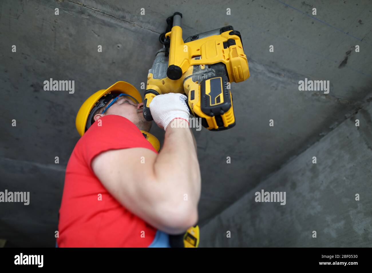 Builder works on ceiling with puncher for concrete Stock Photo - Alamy