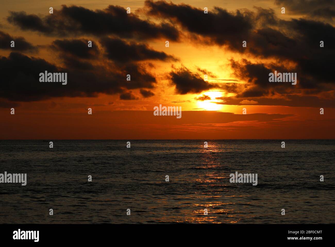 Sunset over the sea, orange sun is reflected in dramatic waves ...