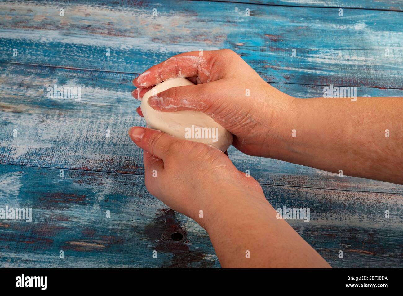 Someone is soaping their hands with a piece of toilet soap on a wooden ...