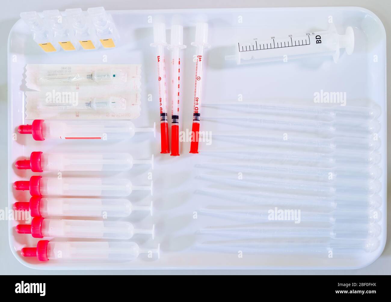 Empty pipettes, droppers, vails and syringe on white tray on laboratory ...