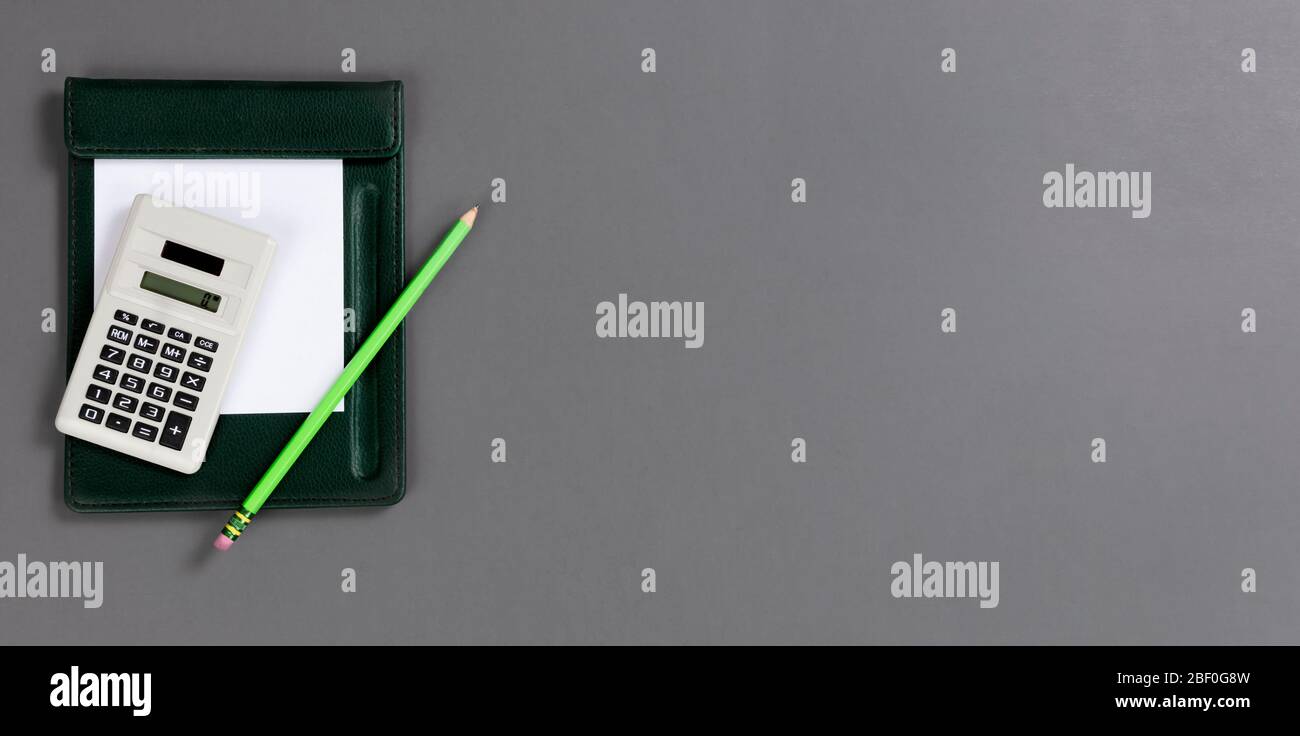 Small calculator with traditional paper and pencil on a gray table top ...
