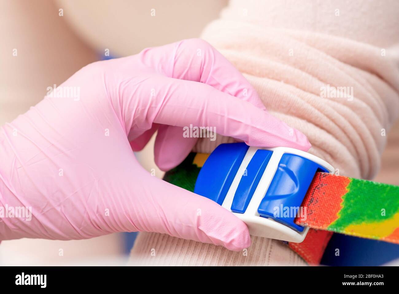 Nurse hand is tightening the harness on the arm to take blood from a ...