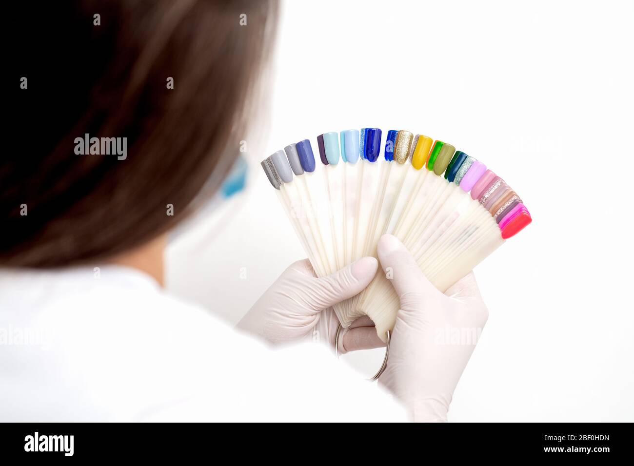 Manicure master holding manicure nail color samples palette on white ...