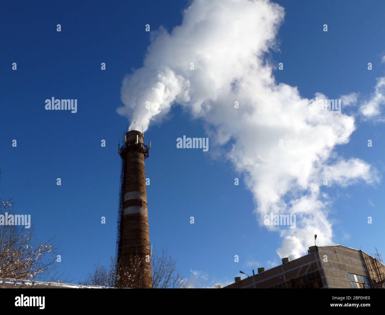 Pipes of an old factory throw clouds of poisonous white smoke into the ...