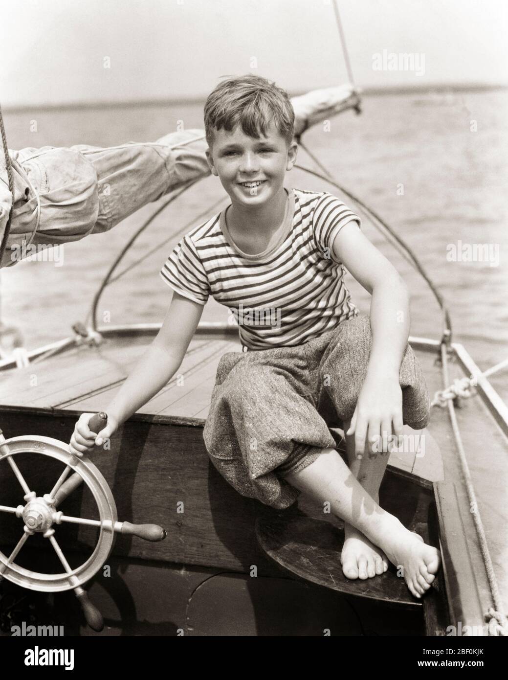 1930s SMILING TOWHEADED ENTHUSIASTIC BAREFOOTED BOY SITTING AT THE ...