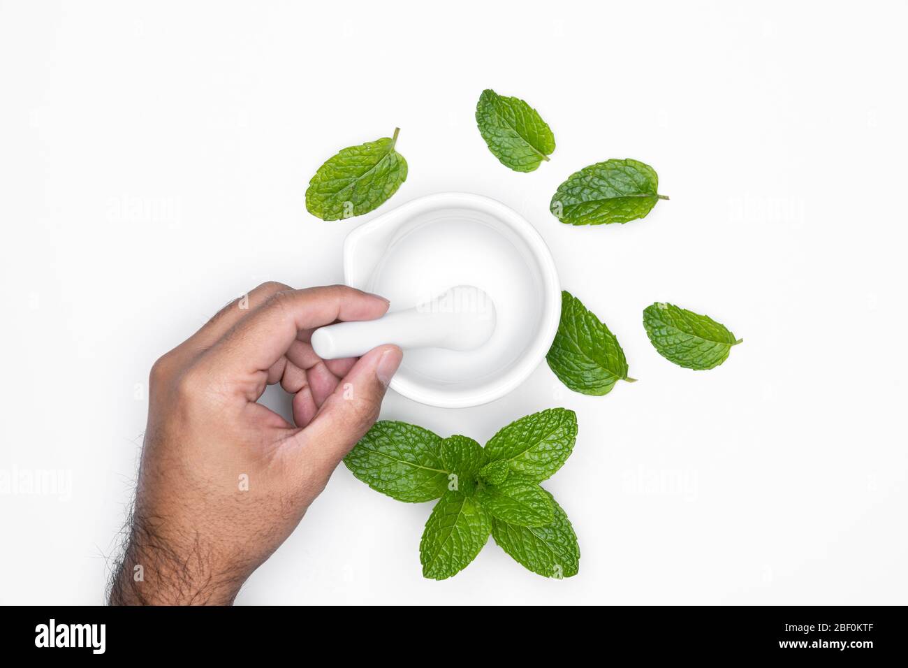 Man hand with mortar grind and herbs isolated on white background. For ...