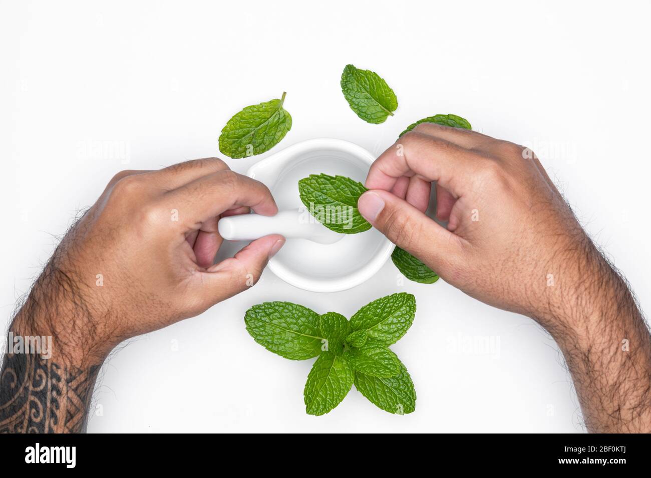 Man hand with mortar grind and herbs isolated on white background. For ...