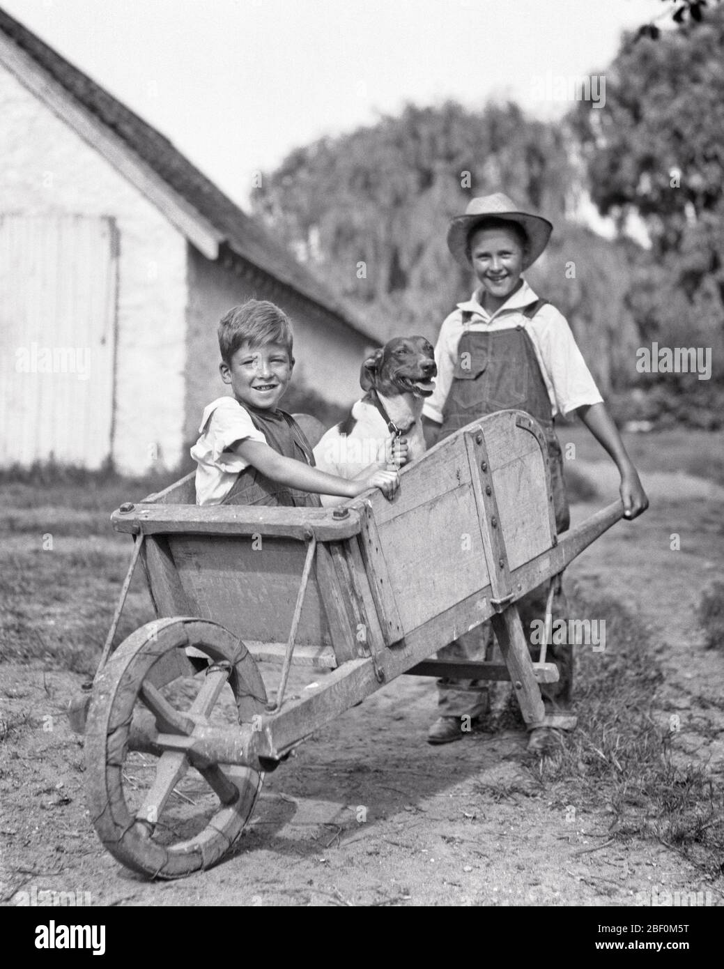 1930s SMILING BOY WEARING STRAW HAT PUSHING FARMYARD WOODEN WHEEL ...