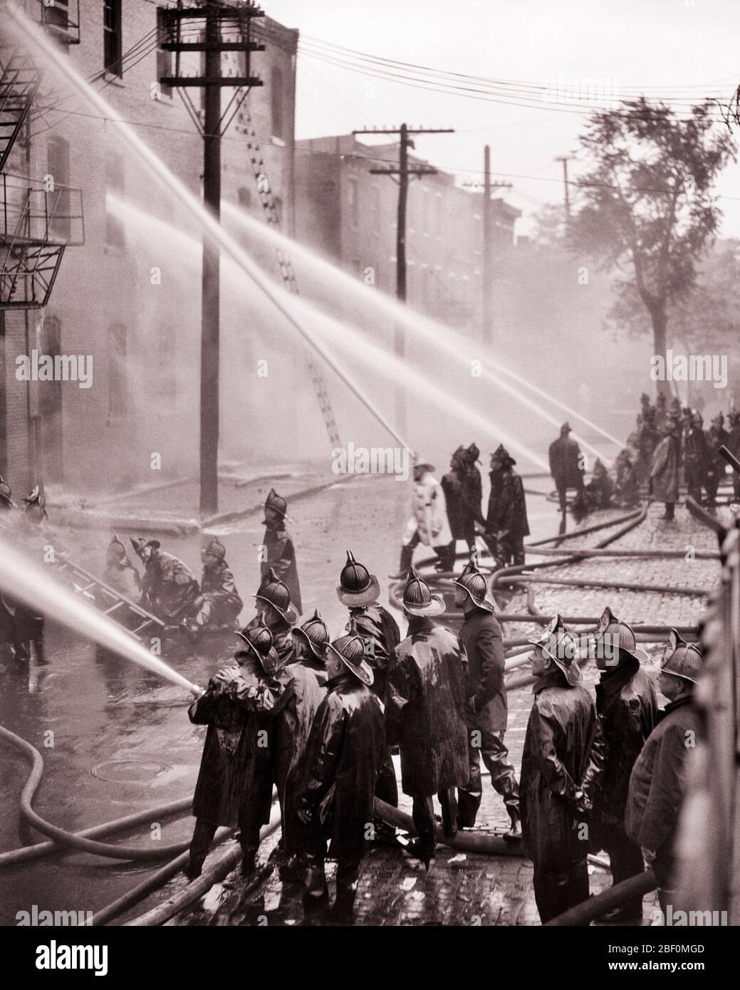 1930s SEVERAL URBAN FIRE COMPANIES MANNING HOSES AND LADDERS AT FIRE OF ...