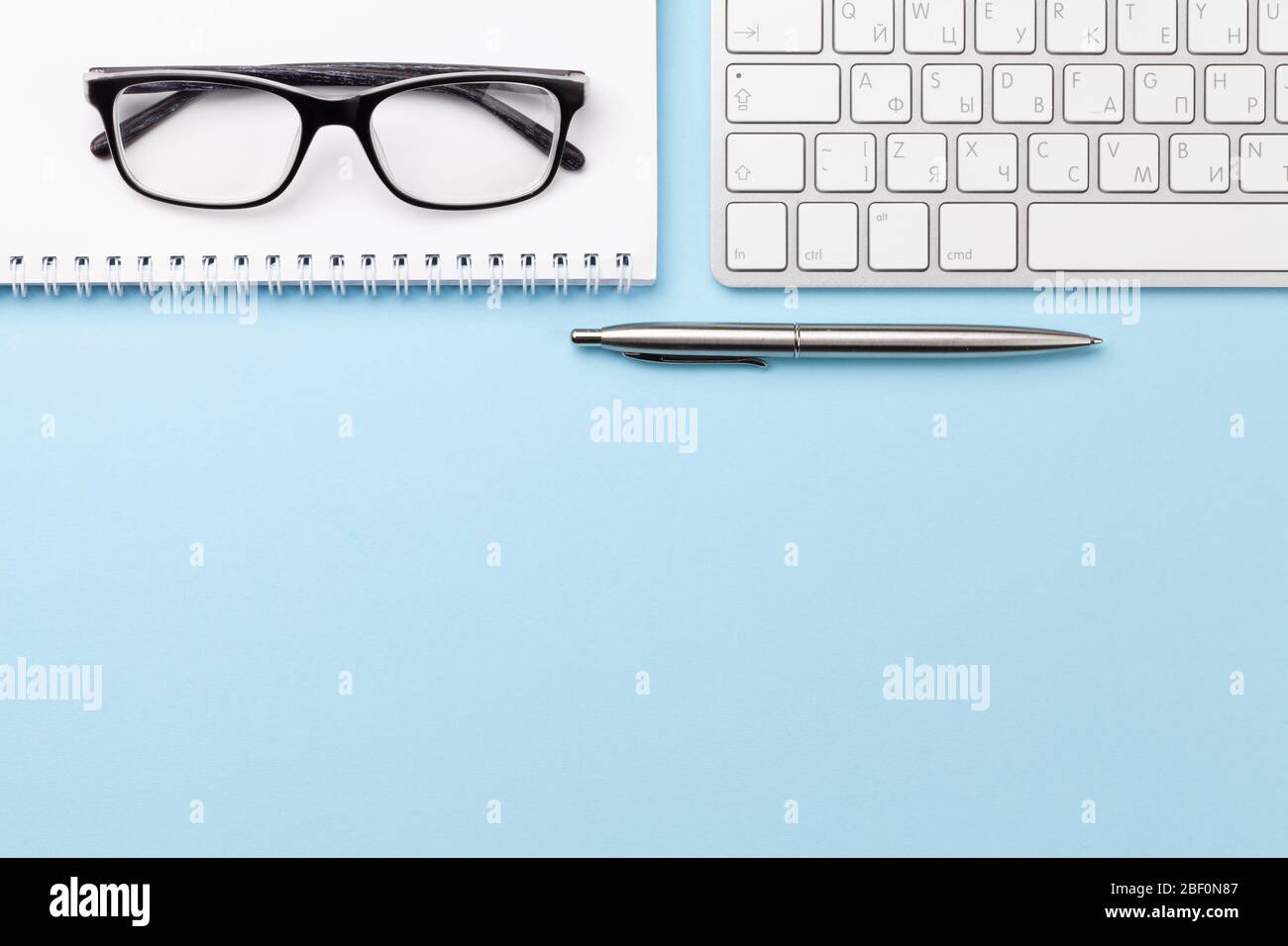 Blue workplace desk table with computer, supplies and glasses. Top view ...