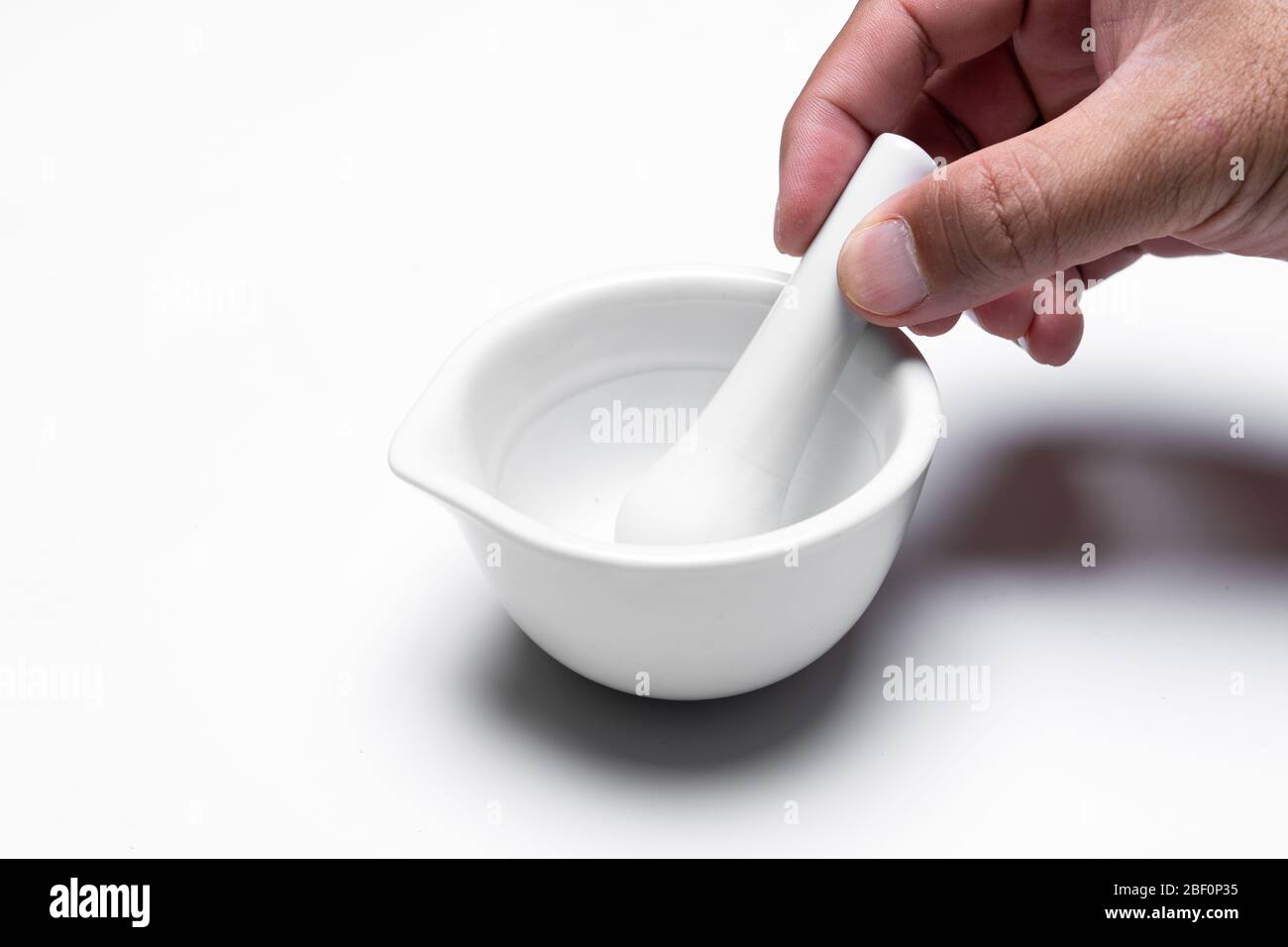 Man hand with mortar grind and herbs isolated on white background. For ...