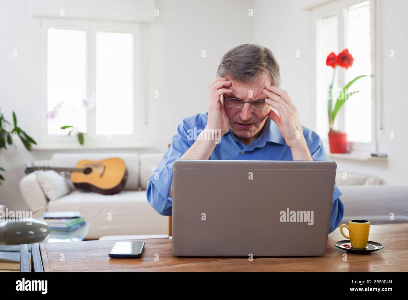 Frustrated businessman working in home office with laptop - focus on ...