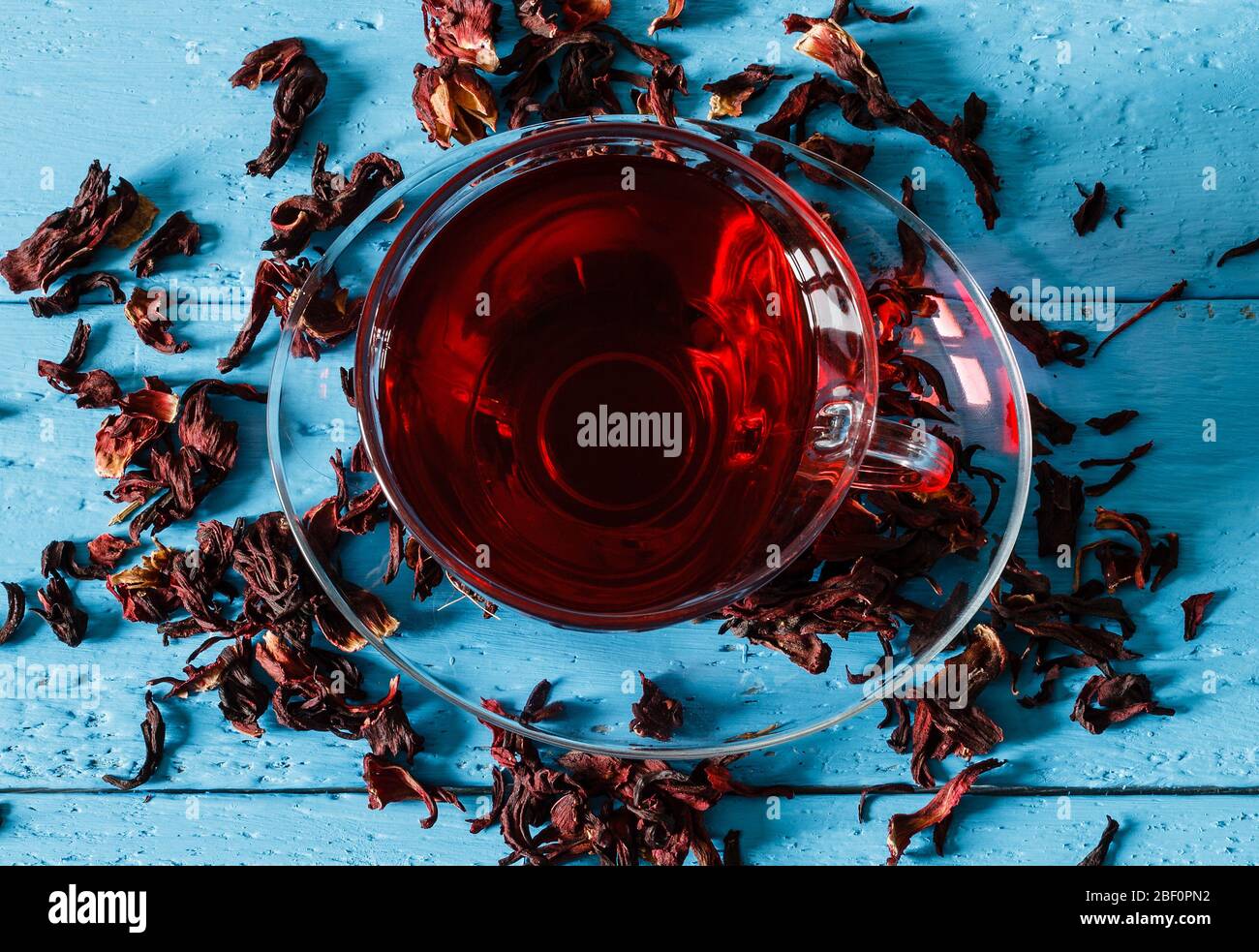 Cup of Karkadeh Red Tea with Dry Flowers on a blue wooden table Stock ...