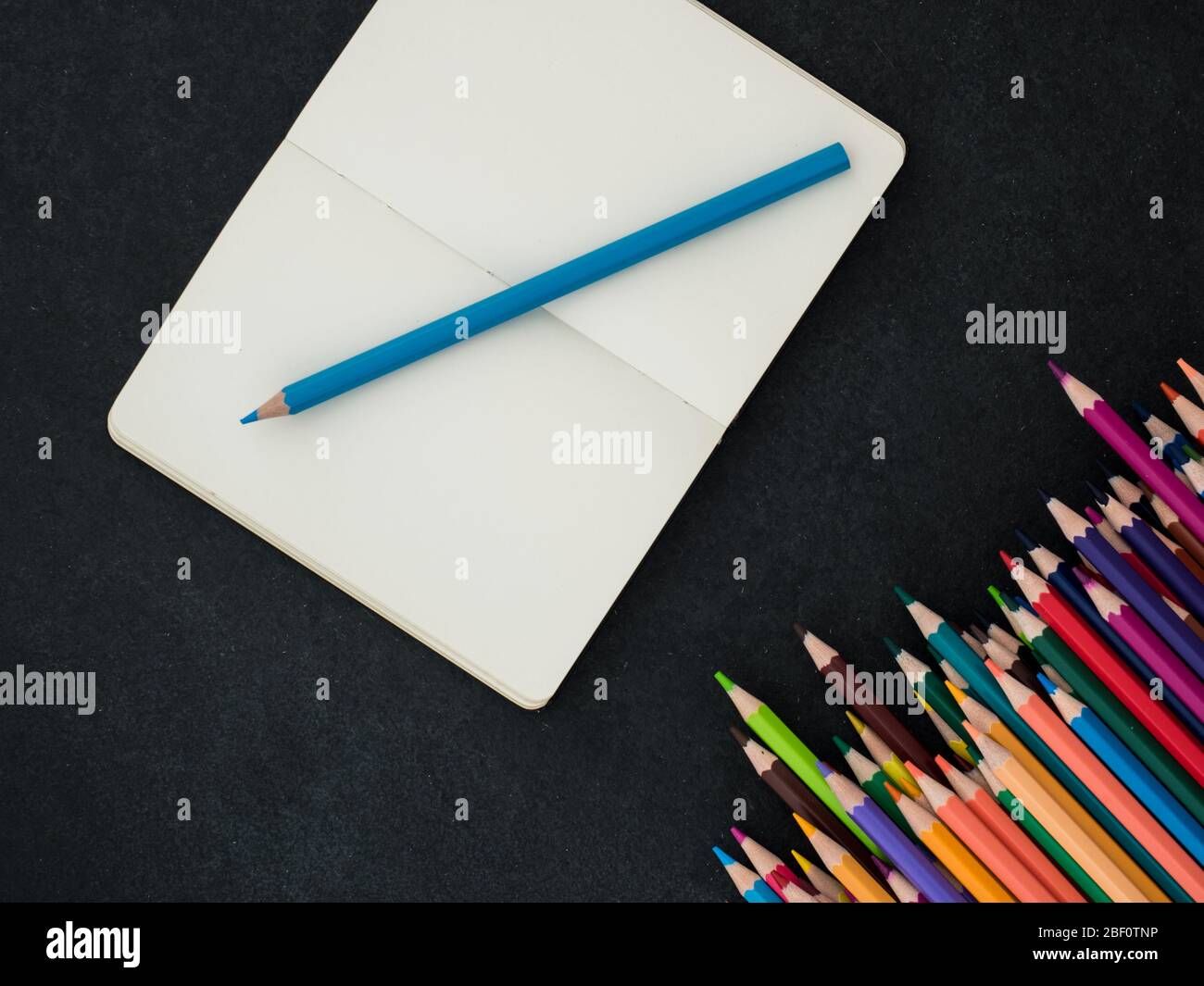 Set of colored pencils and notebook on slate background. top view Stock ...