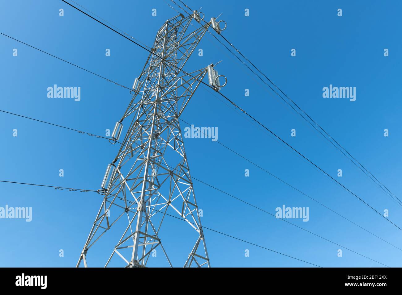 Electricity transmission pylon silhouetted against blue sky Stock Photo ...