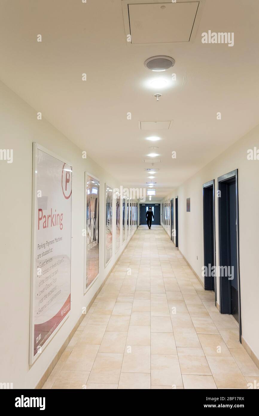 Corridor with lighting and person walking to doors at parking garage ...