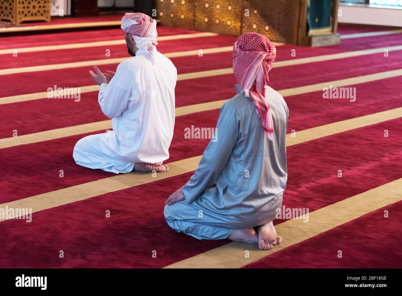 Two muliethnic religious muslim young people praying and reading Koran ...