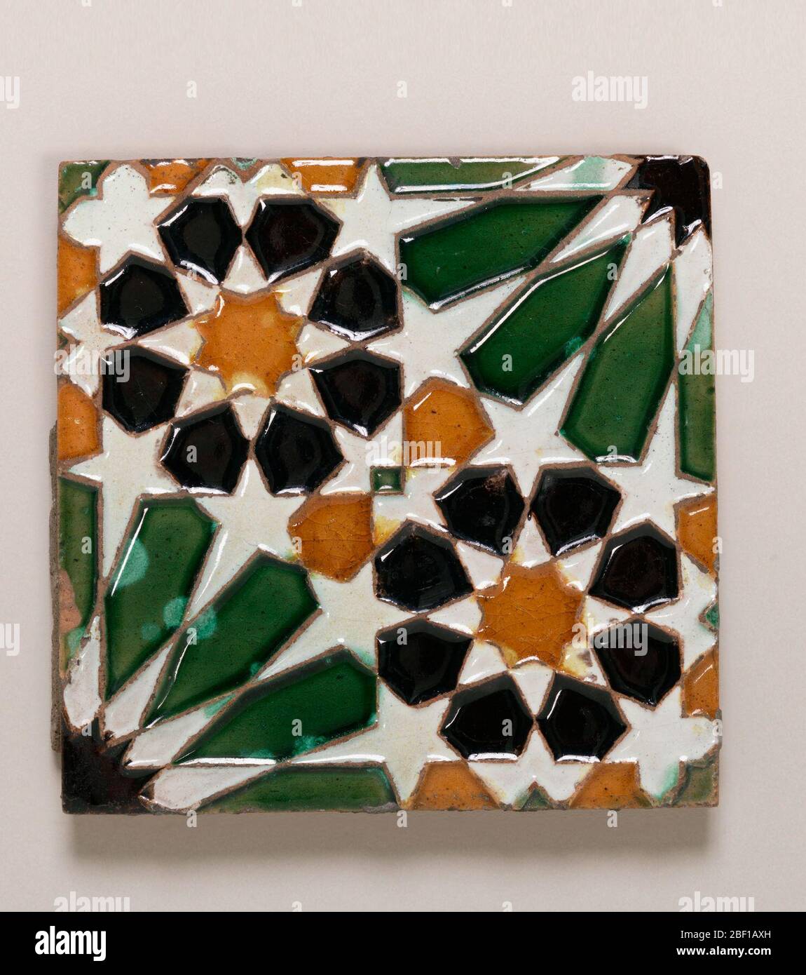 Tile. Red earthenware with white slip. Geometric interlaced pattern ...