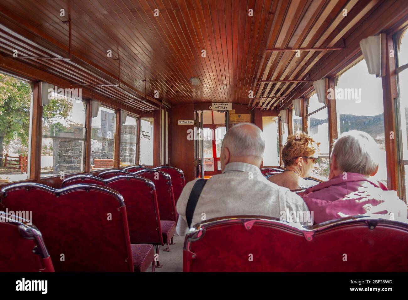 Tourist passengers sitting inside a restored train carriage on a narrow ...