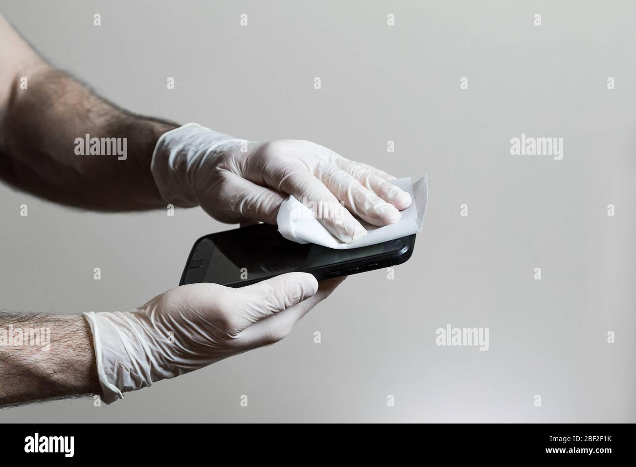 A mans hands wearing latex gloves wiping off his cell phone with a ...