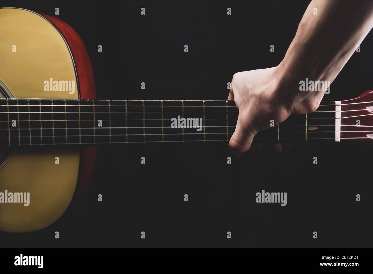 Hand holds acoustic guitar. musical instrument on black background ...