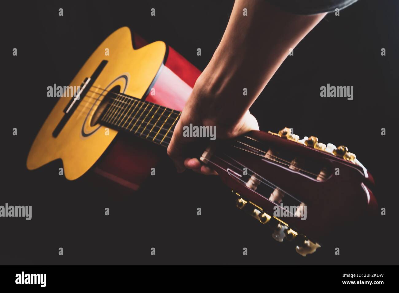Hand holds acoustic guitar. musical instrument on black background ...