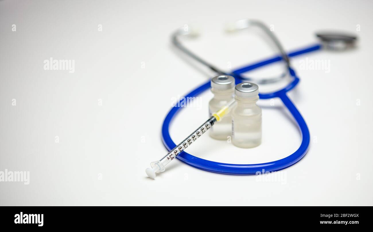 An empty syringe on two medical vials with a blue stethoscope in the ...