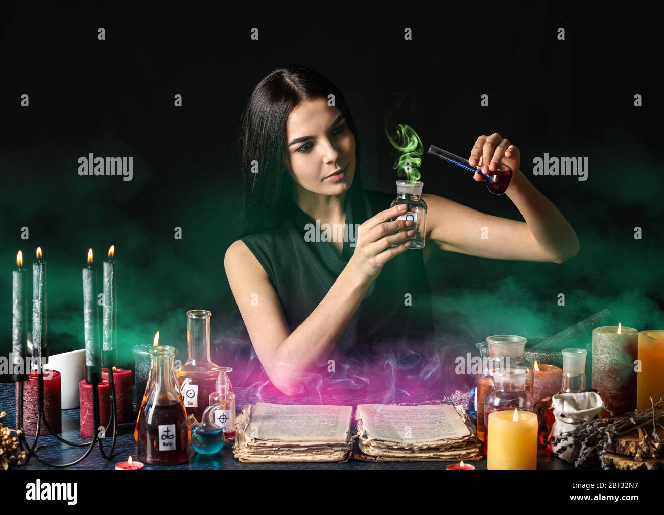 Female alchemist making potion on dark background Stock Photo - Alamy