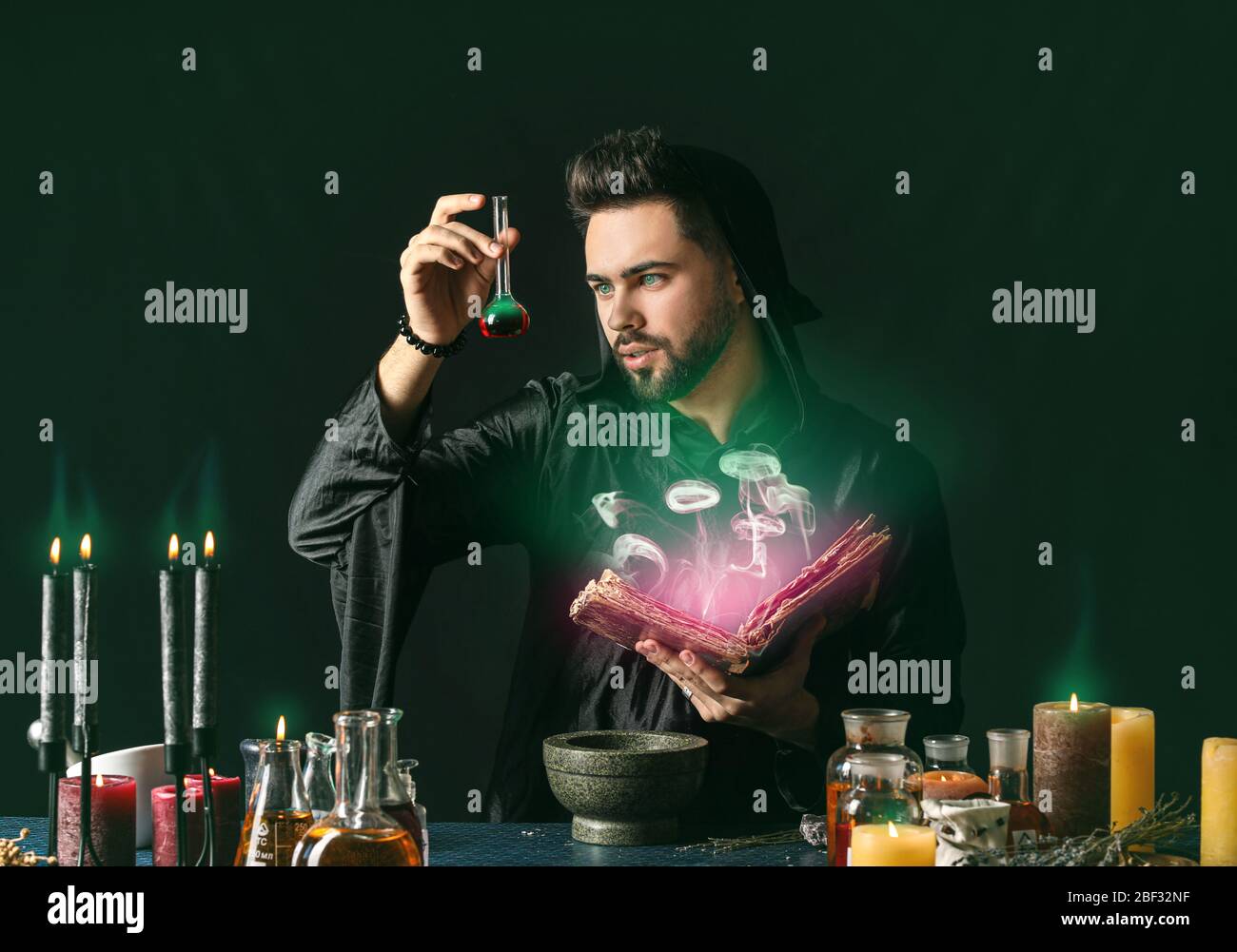 Male alchemist making potion on dark background Stock Photo - Alamy