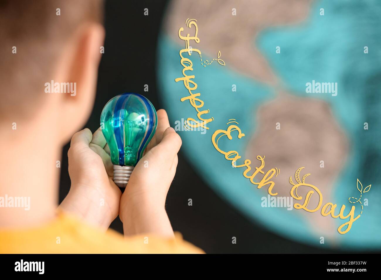 Little boy with light bulb on blurred background. Earth Day celebration ...