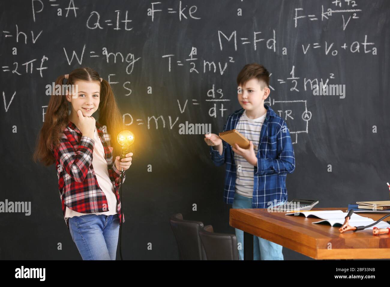 Cute little children near blackboard at physics lesson in classroom ...