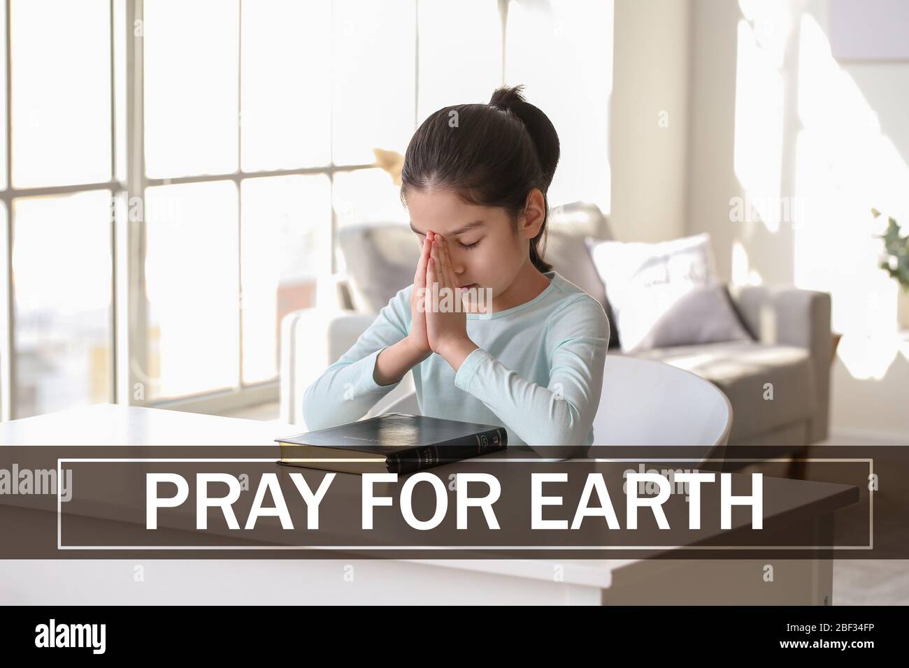 Cute little Asian girl praying for Earth at home Stock Photo - Alamy