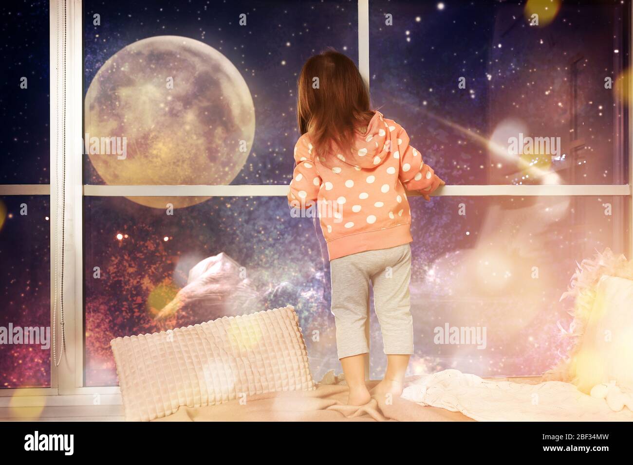 Cute little girl near window in bedroom at night Stock Photo - Alamy
