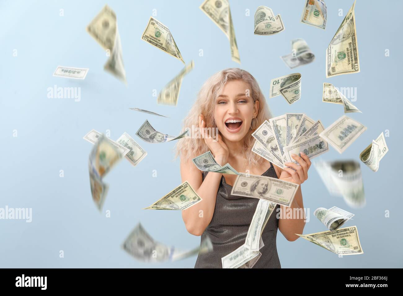 Beautiful young woman with flying money on grey background Stock Photo ...