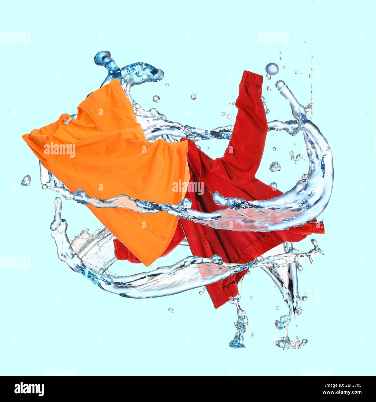 Clean flying clothes with splashes of water on color background Stock ...