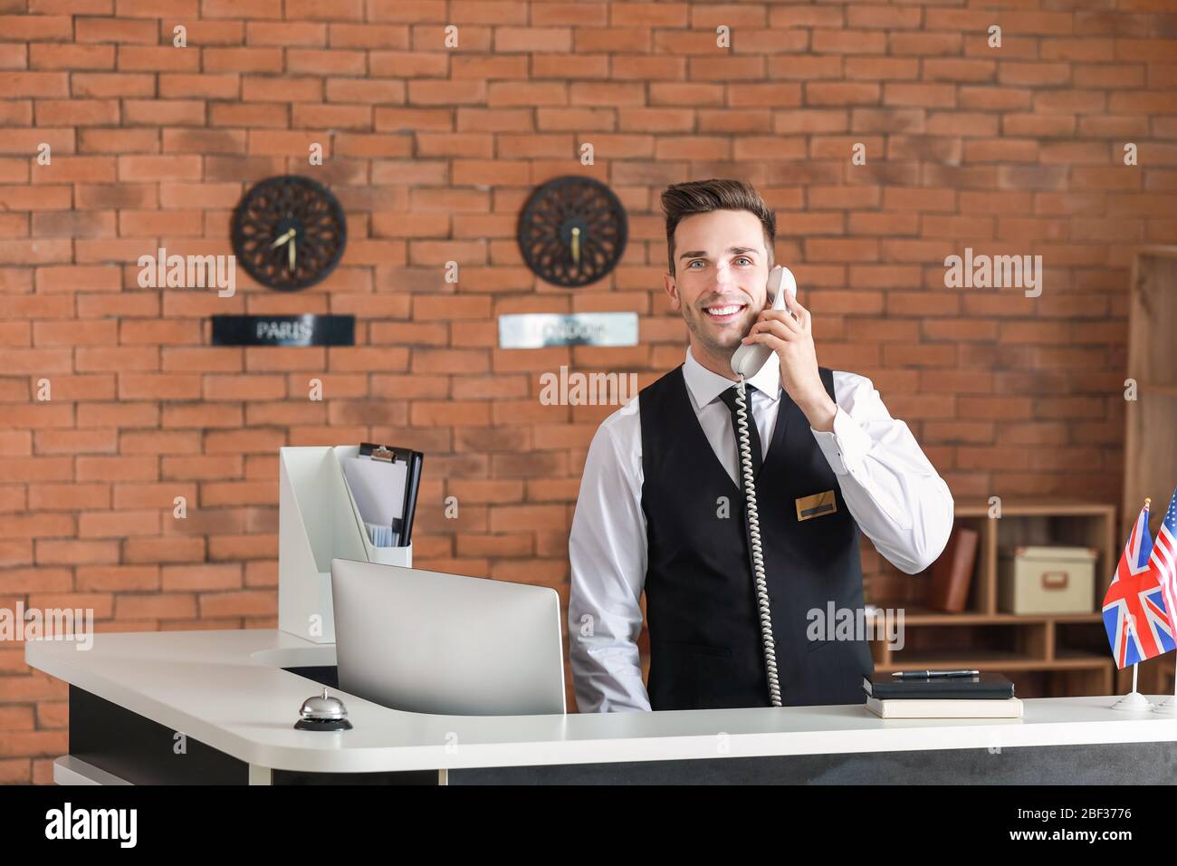 Male receptionist talking on phone in hotel Stock Photo - Alamy