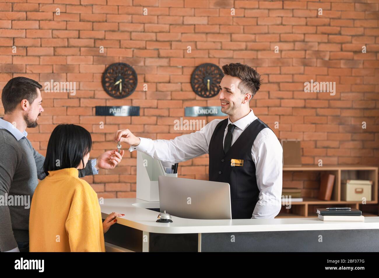 Couple receiving keys from hotel room at reception Stock Photo - Alamy
