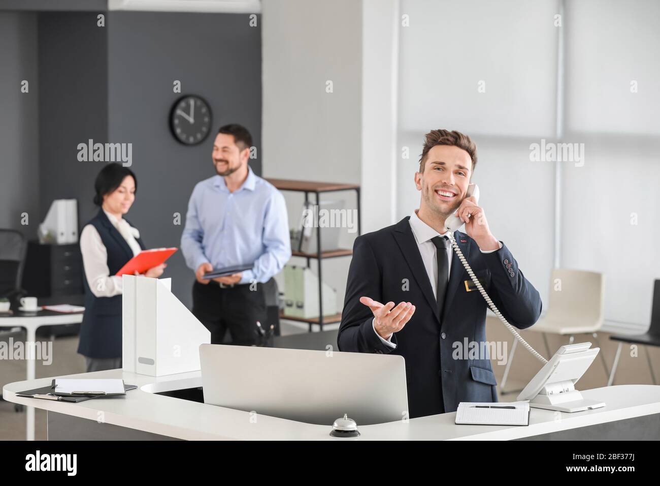 Male receptionist talking on phone in office Stock Photo - Alamy