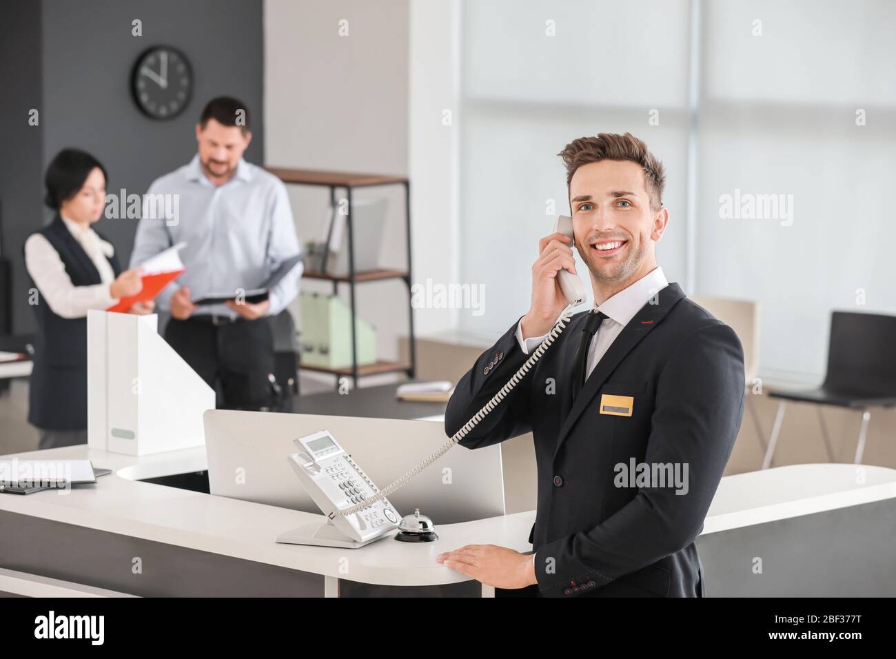 Male receptionist talking on phone in office Stock Photo - Alamy
