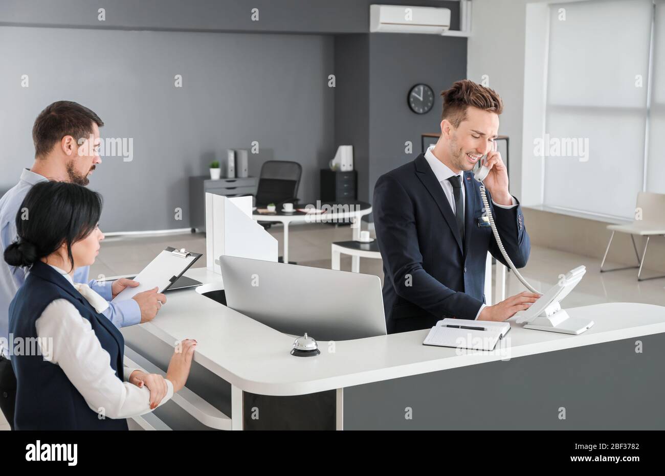 Male receptionist talking on phone in office Stock Photo - Alamy