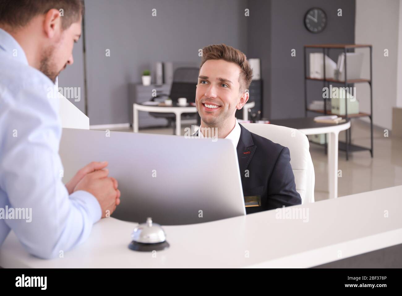 Male receptionist working with visitor in office Stock Photo - Alamy