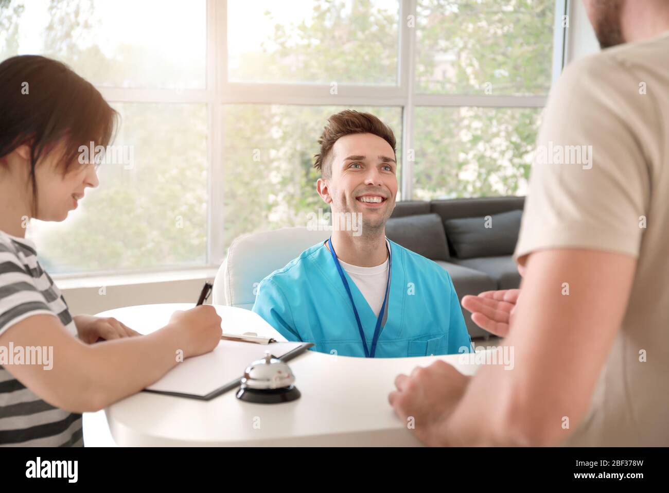 Male receptionist working with patients in clinic Stock Photo - Alamy