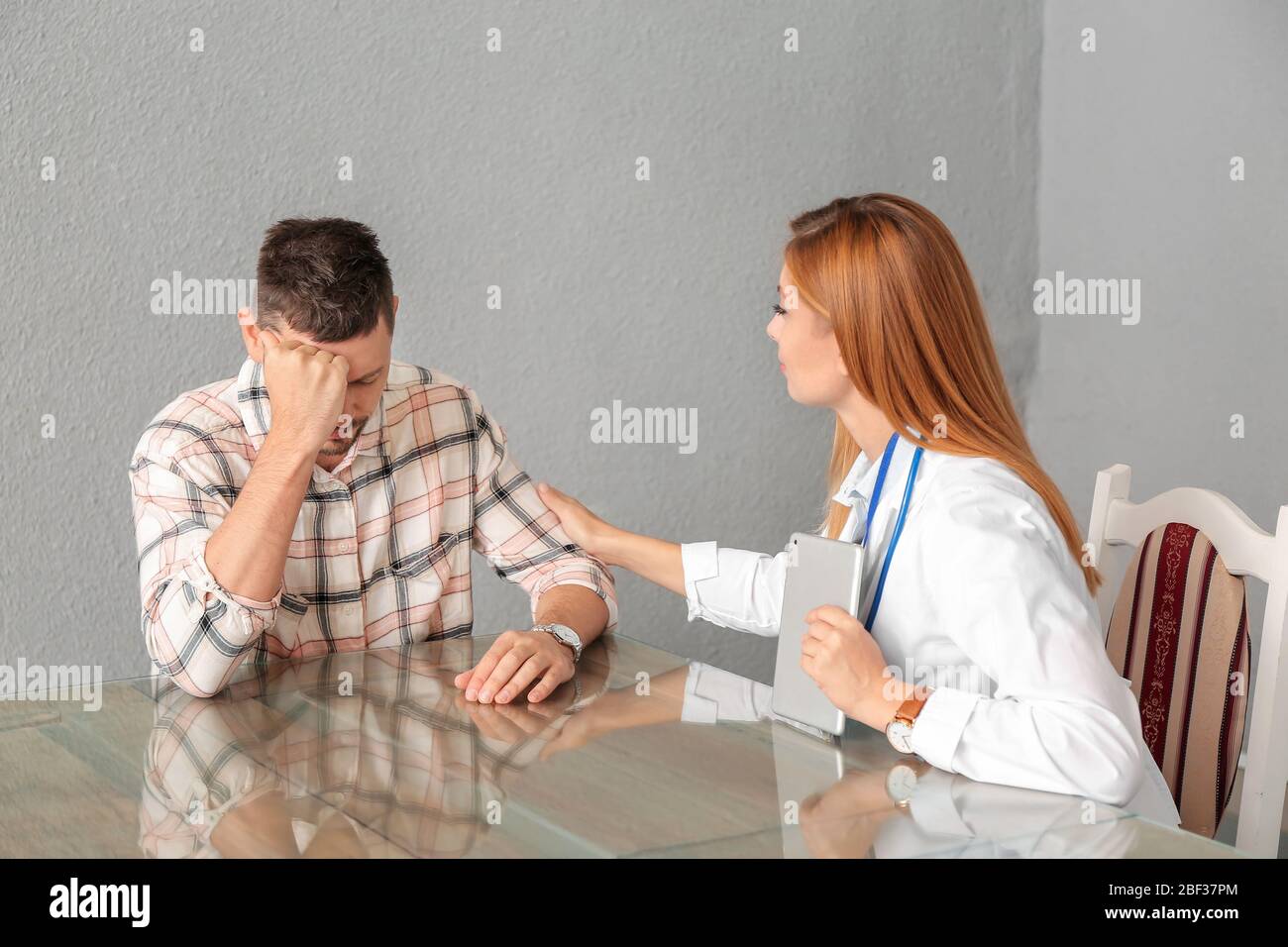 Female doctor calming sad patient in clinic Stock Photo - Alamy
